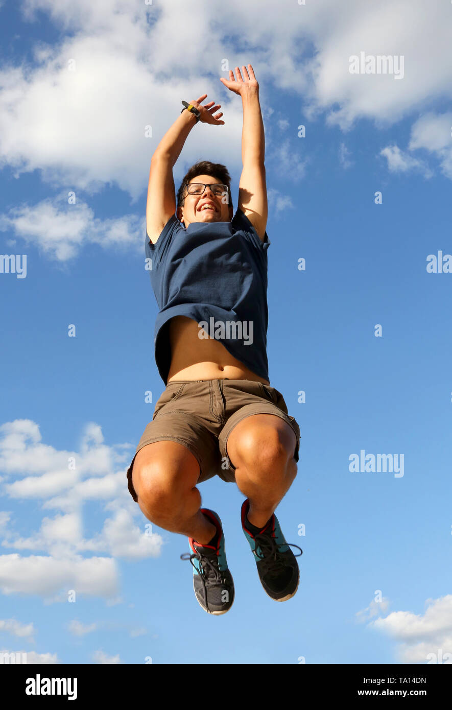 young boy jumps on blue sky with clouds Stock Photo - Alamy