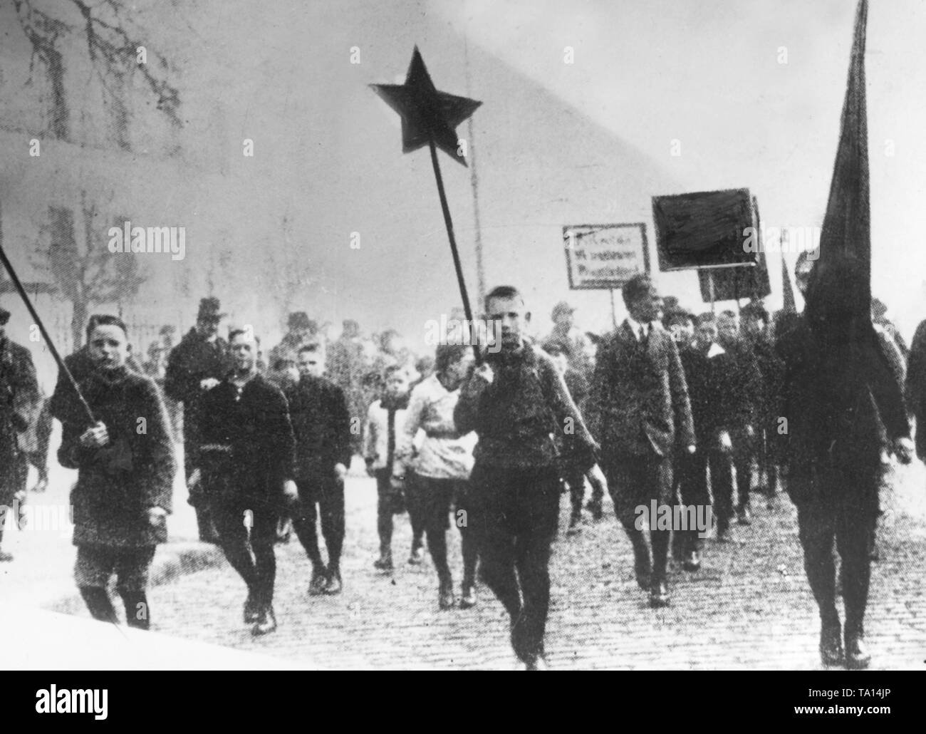 Members of a Communist youth union march with signs and red stars ...