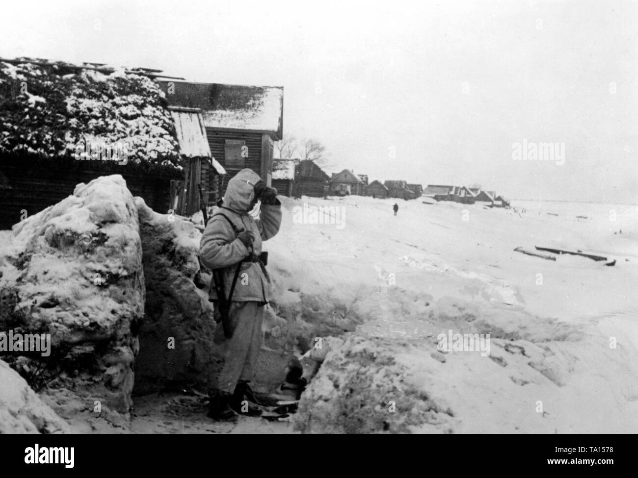 A German soldier in camouflage watches the frozen and snow-covered lake ...