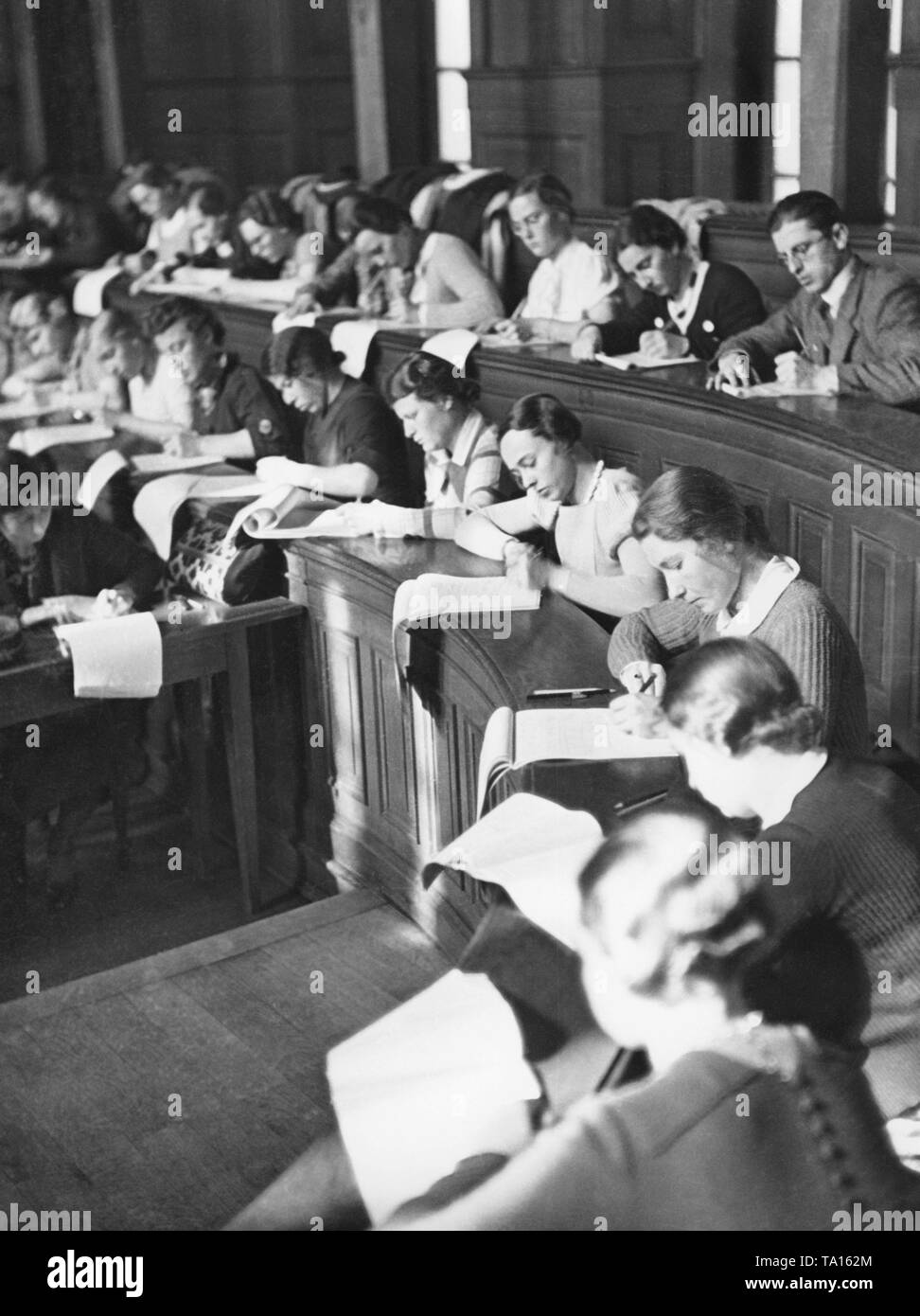 Predominantly female students take note on paper notepads during the ...