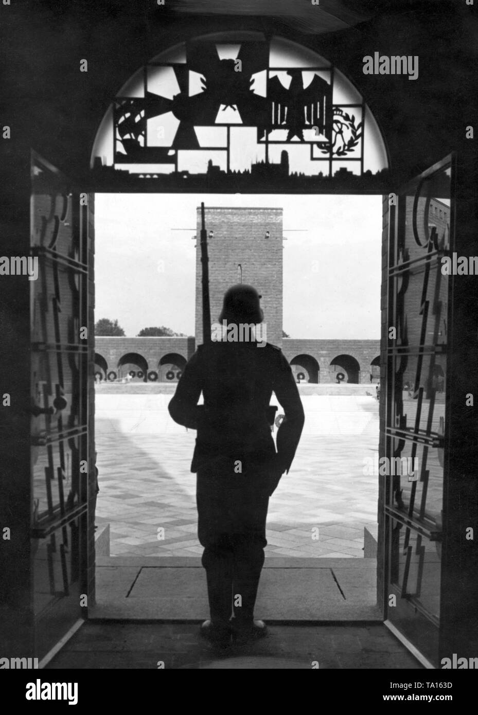 A soldier as a guard of honor standing in front of the flag tower of ...