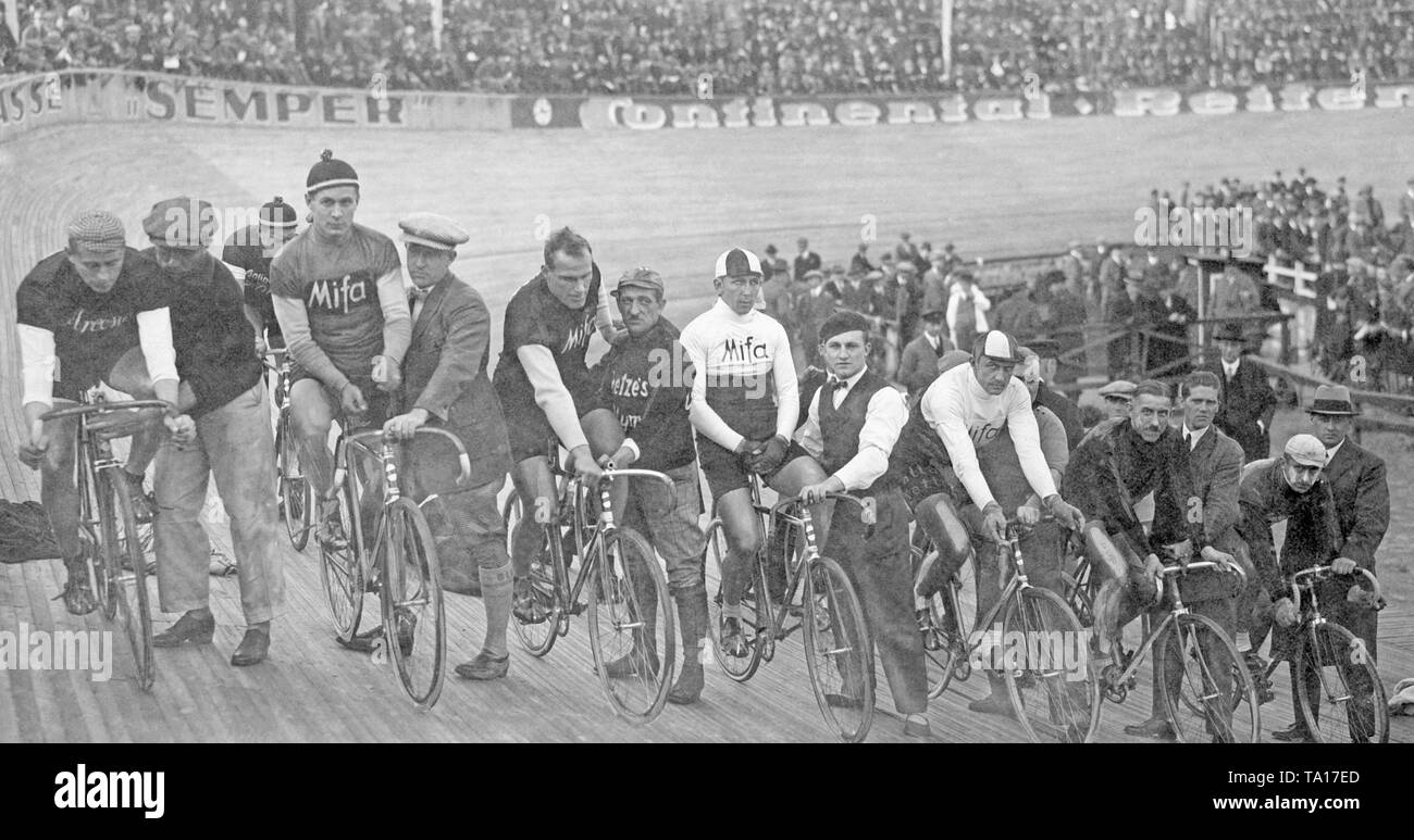 Several racers and their helpers are ready to start a track cycling ...