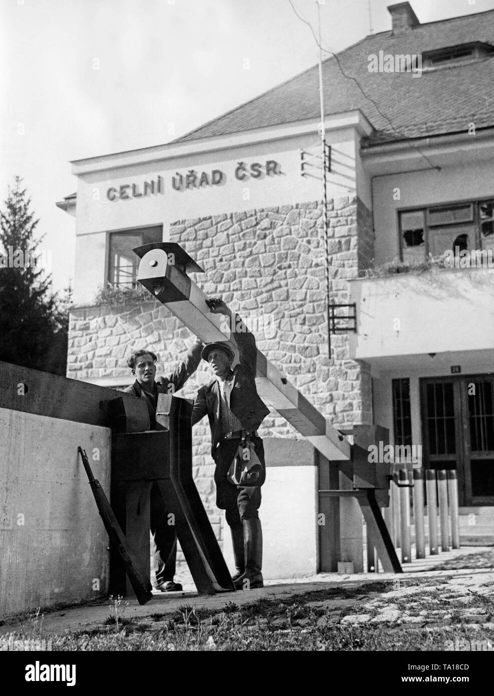 Two armed men open the tollgate of a border crossing at the German ...