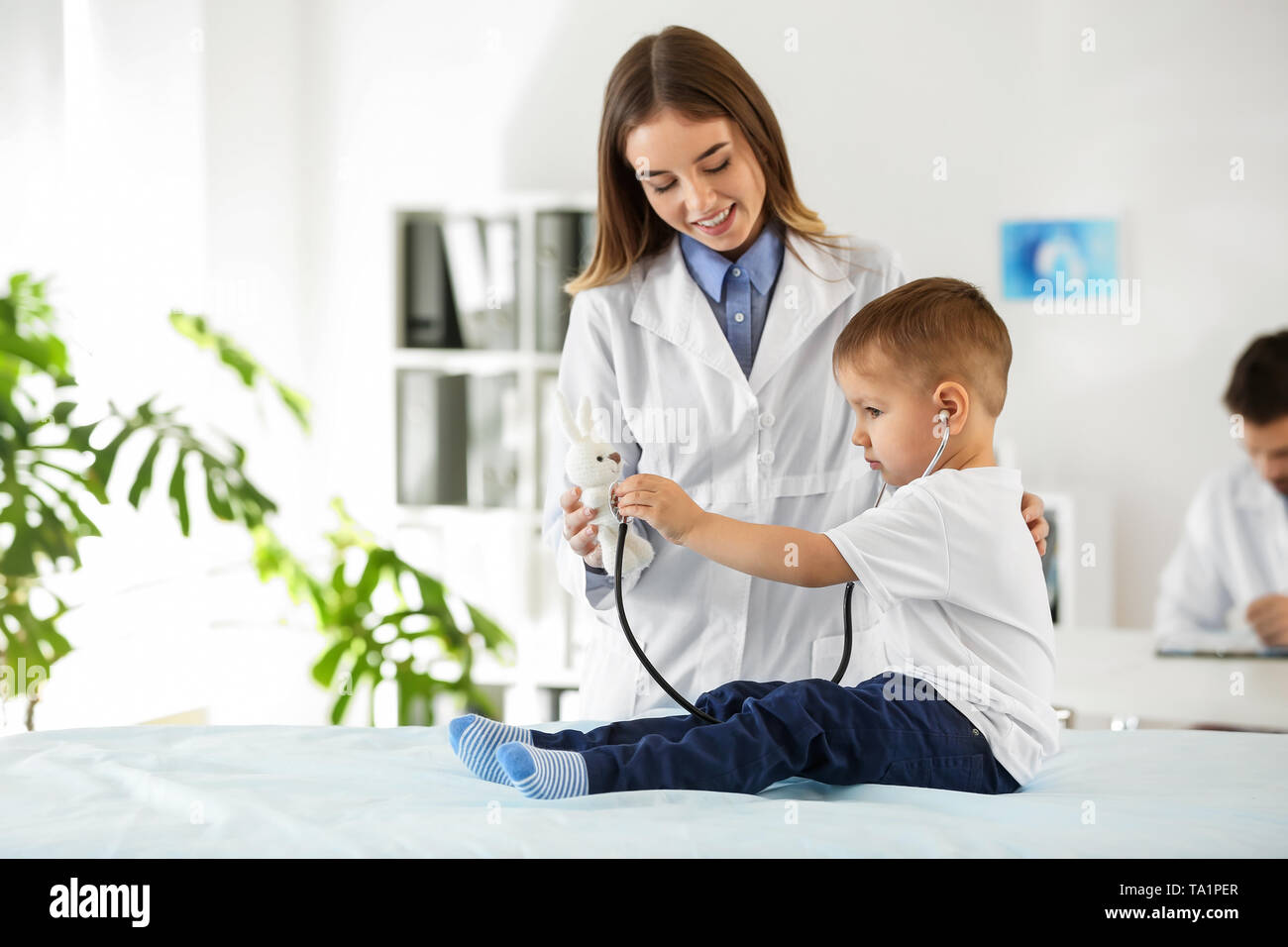 Female doctor working with cute little boy in clinic Stock Photo - Alamy