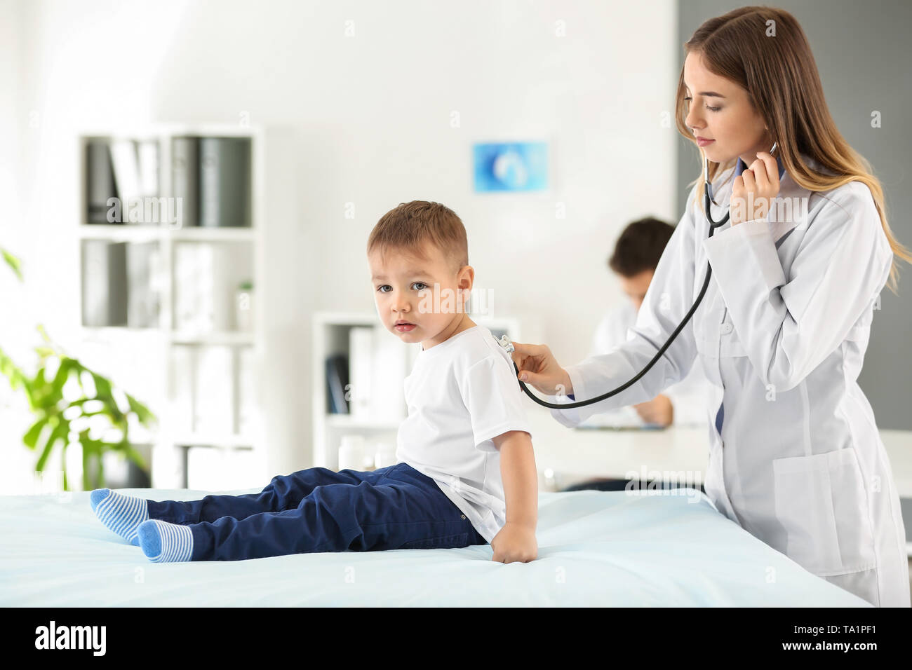 Female doctor working with cute little boy in clinic Stock Photo - Alamy