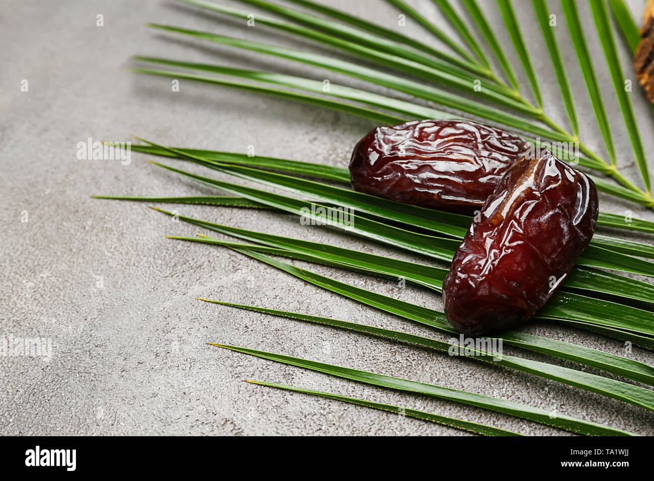 Sweet dried dates and palm leaf on grey background Stock Photo - Alamy