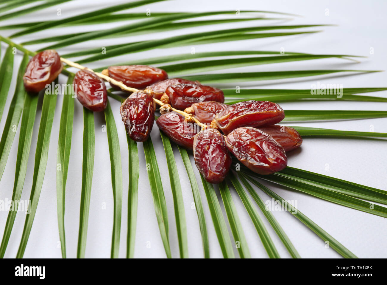 Sweet dried dates and palm leaf on white background Stock Photo - Alamy