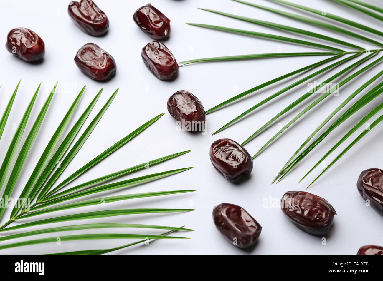 Sweet dried dates and palm leaves on white background Stock Photo - Alamy