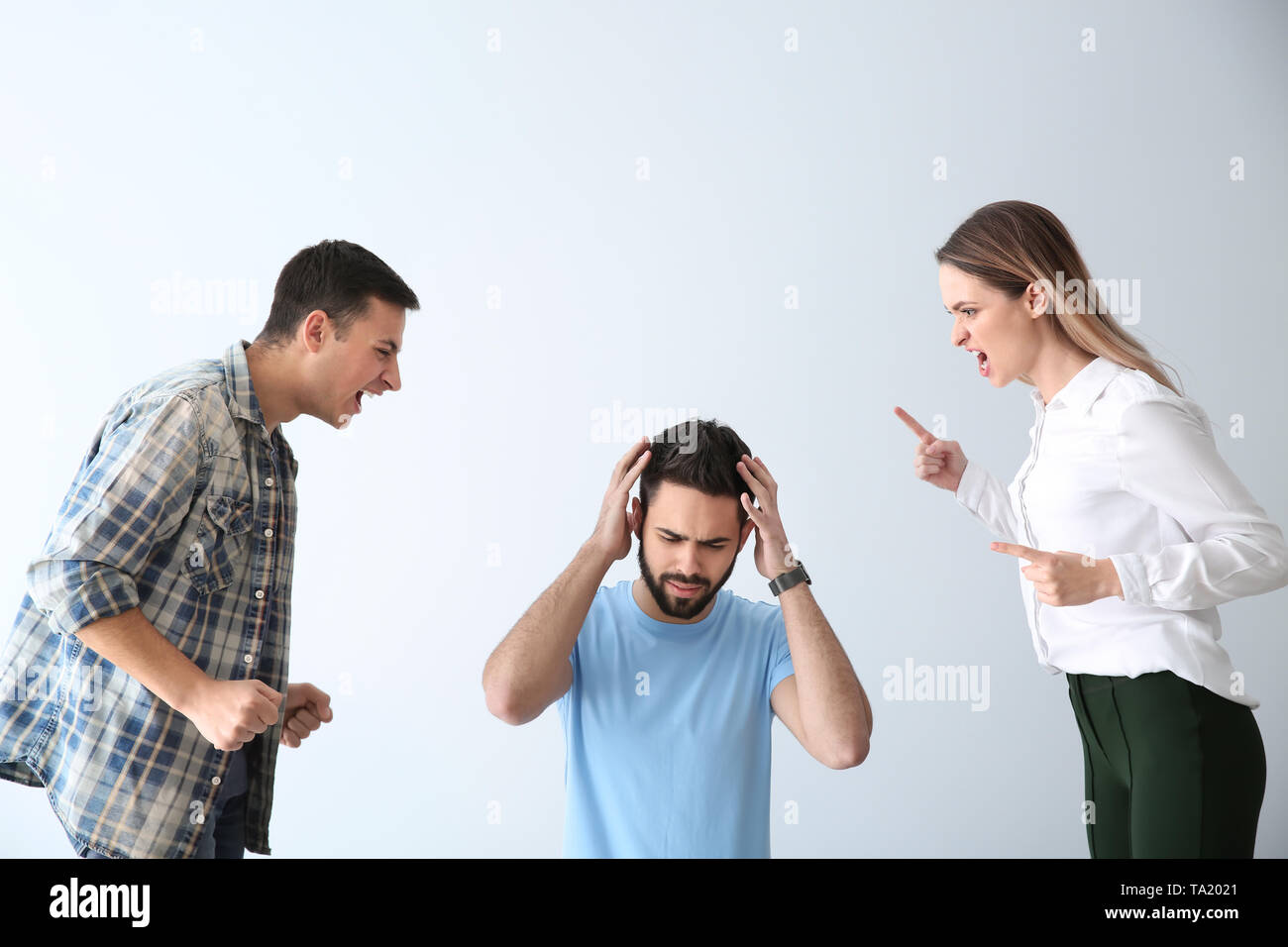 People shouting at young stressed man on white background Stock Photo ...