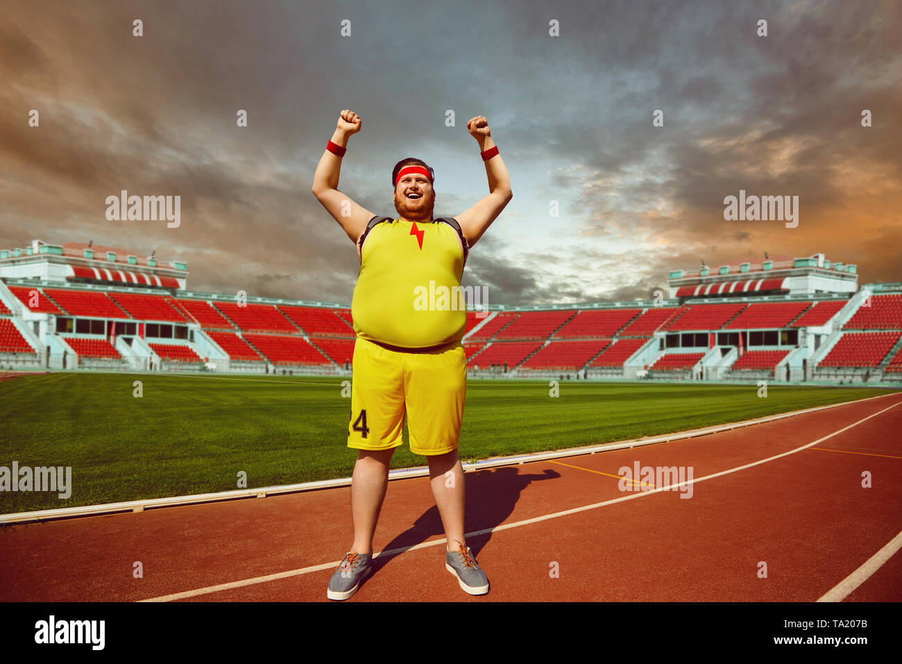 Fat man in sportswear shouts raised hands up standing in the stadium ...