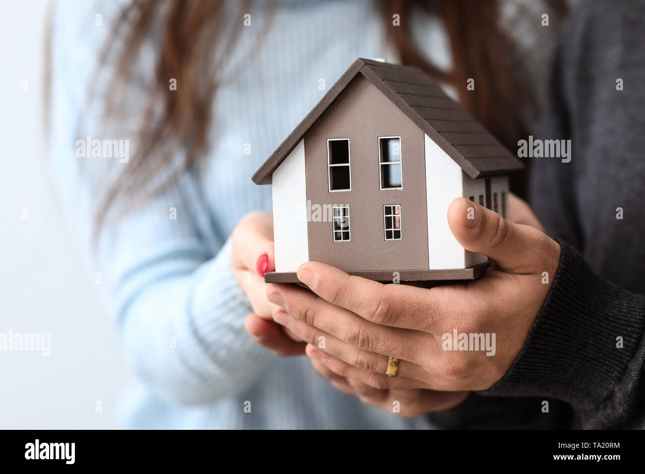 Couple holding figure of house on white background, closeup. Property ...