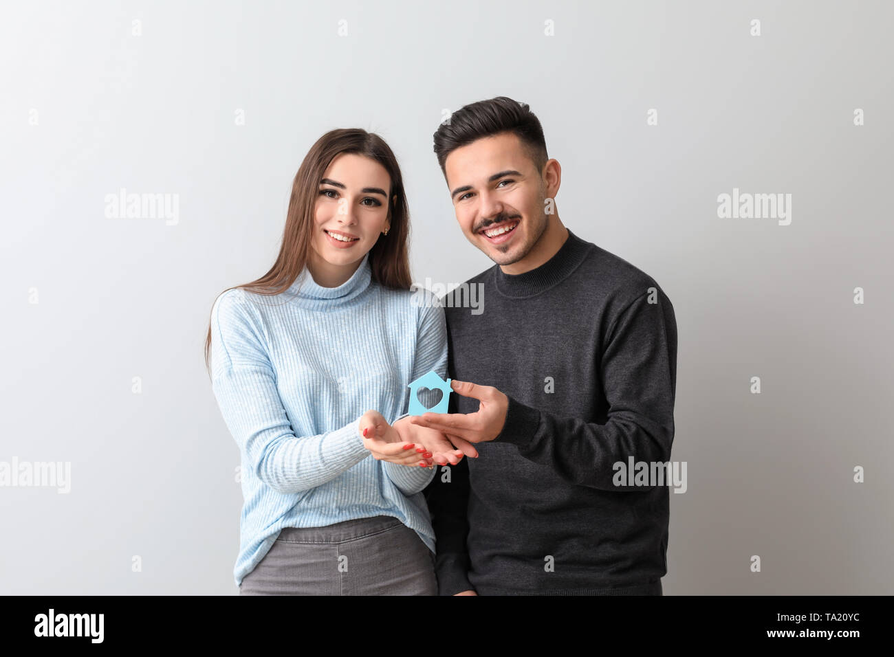 Couple holding figure of house on white background. Property insurance ...