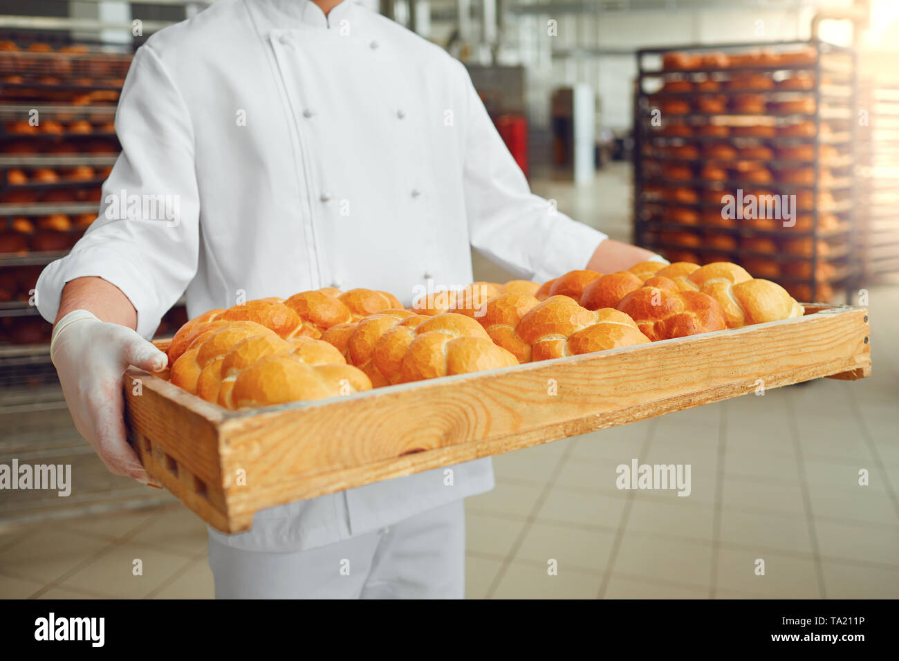 Baker's hands hold a tray with fresh bread at the bakery. Bakery ...