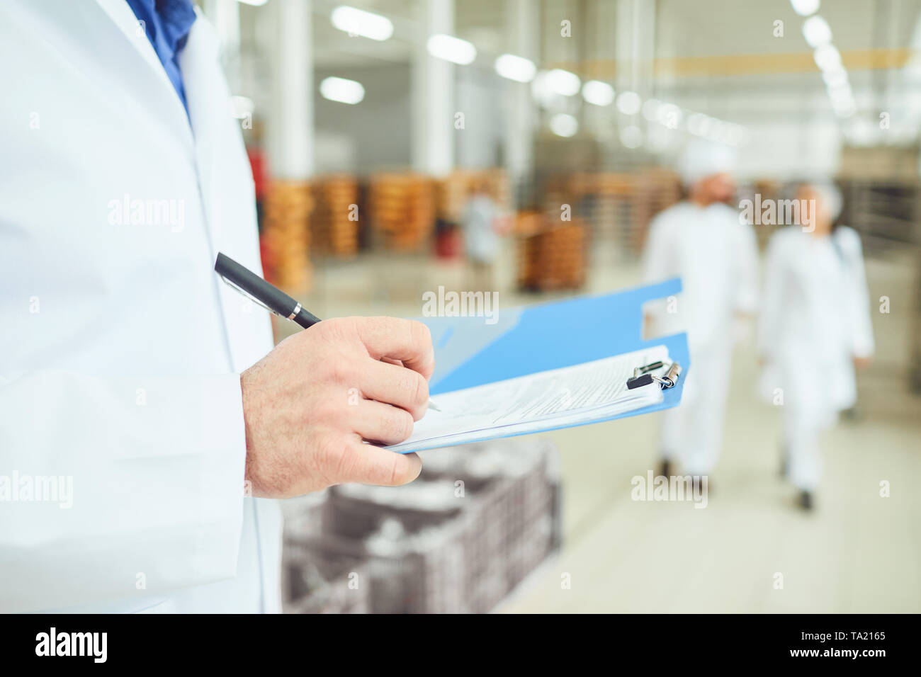Hands of a person in a white coat make an entry in a folder with papers ...