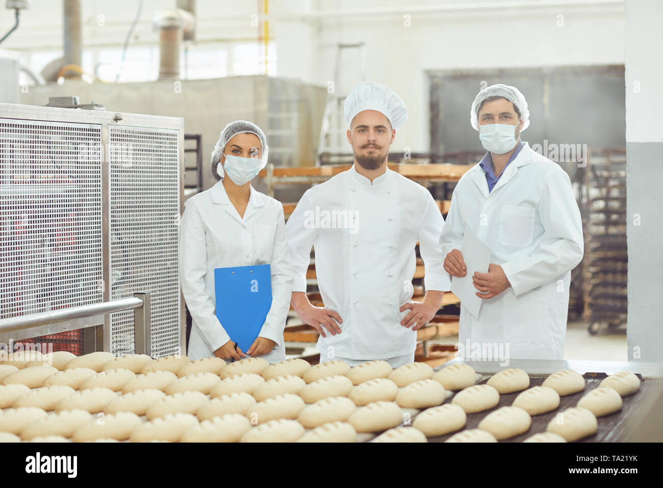 Technologist and baker inspect the bread production line at the bakery ...