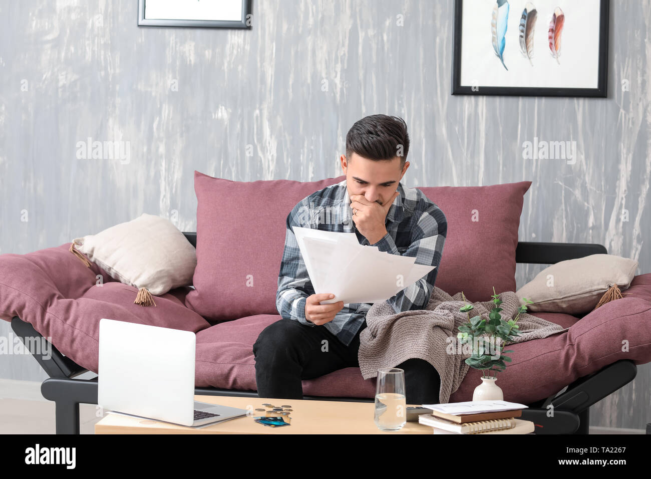 Worried young man in debt at home Stock Photo - Alamy
