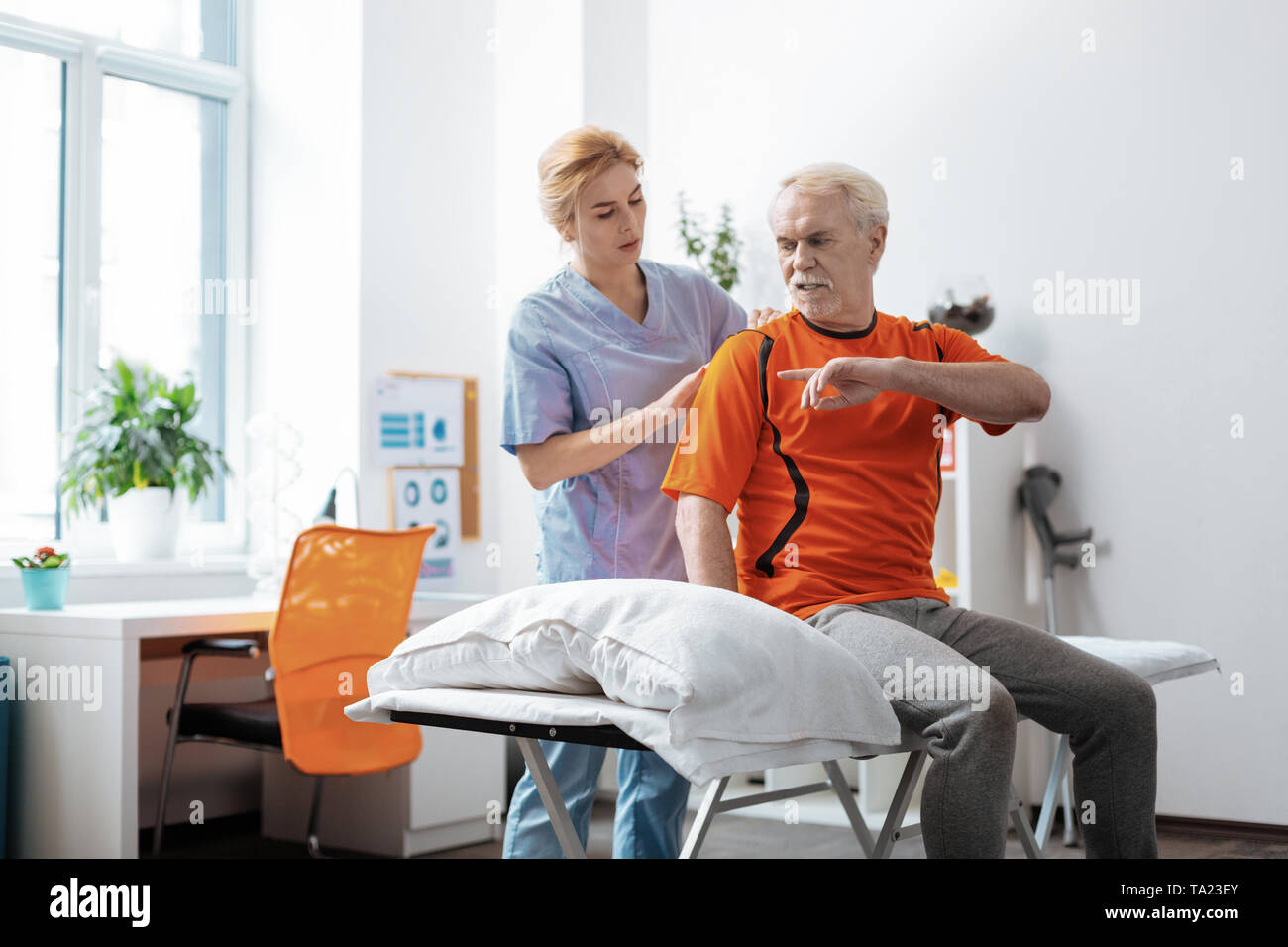 Pleasant aged man pointing at his shoulder Stock Photo - Alamy