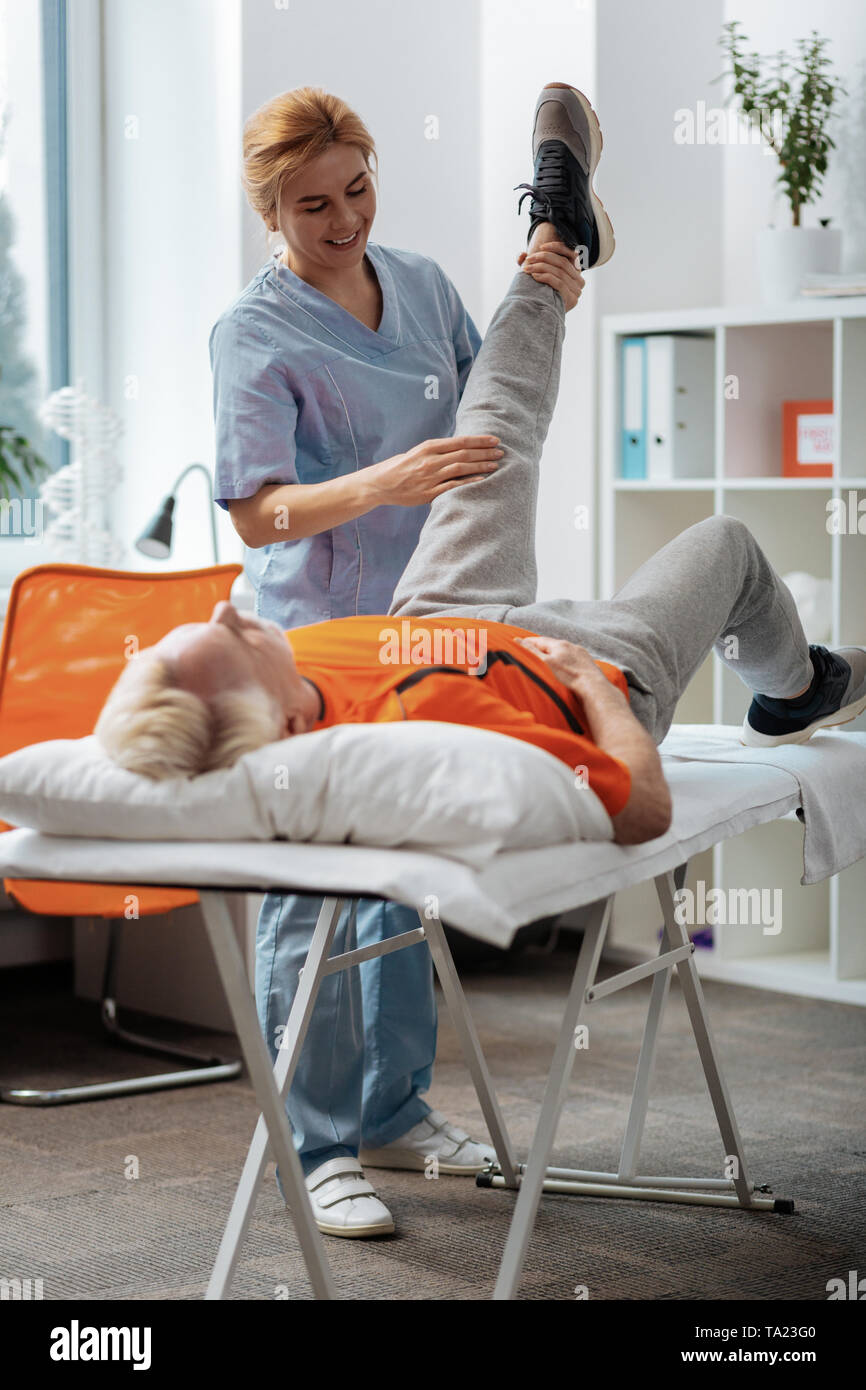 Nice pleasant woman looking at her patients leg Stock Photo - Alamy