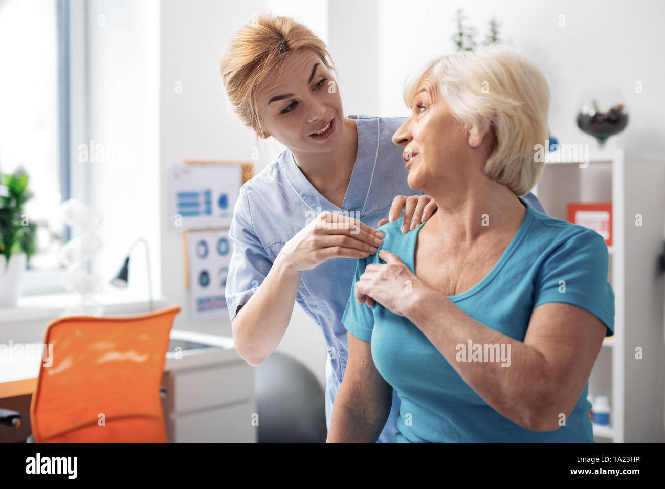 Pleasant aged woman pointing at her shoulder Stock Photo - Alamy