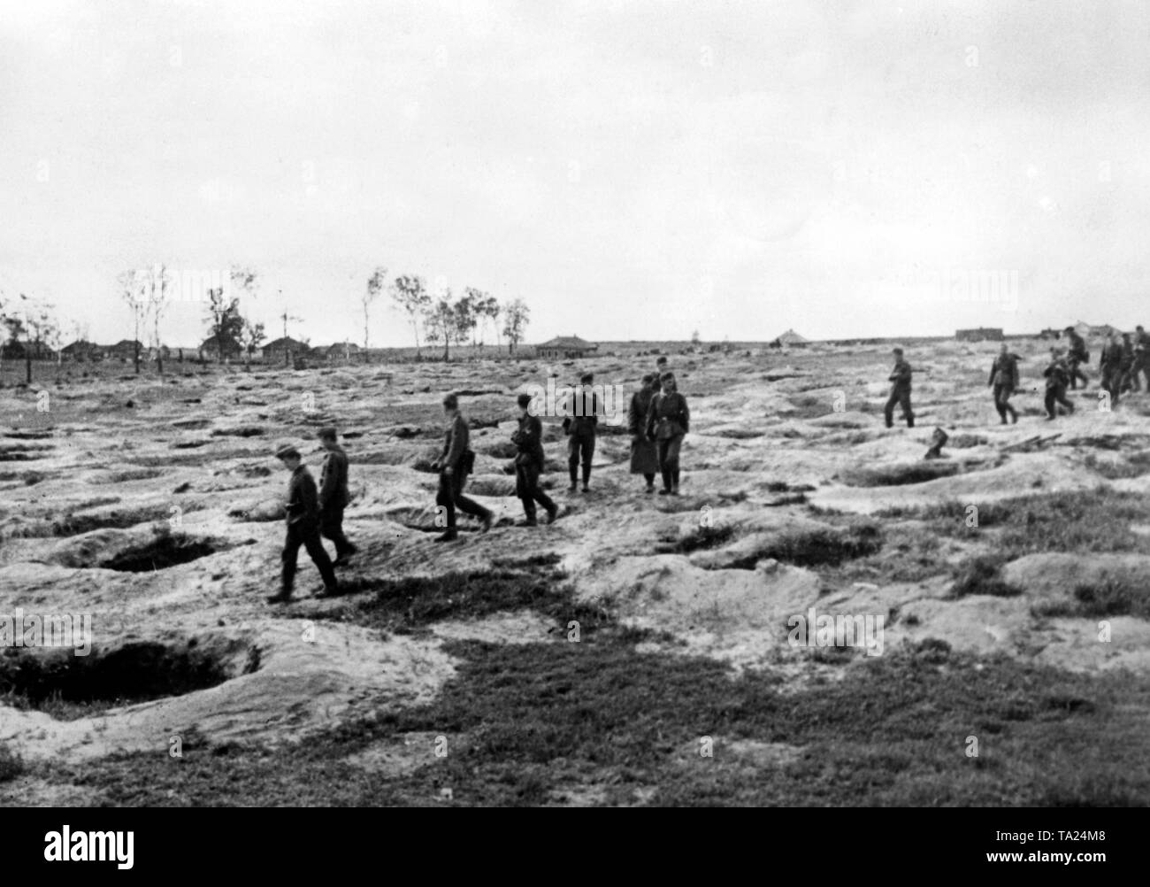 German infantrymen cross a field with gunholes, which had been ...
