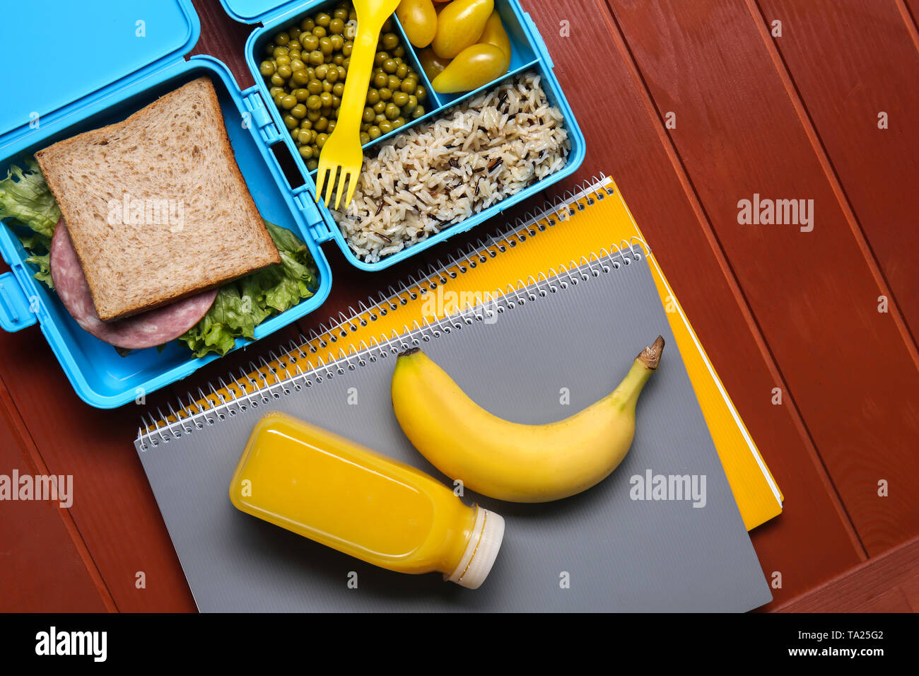 Lunch boxes with tasty food and bottle of juice for kid on table Stock ...