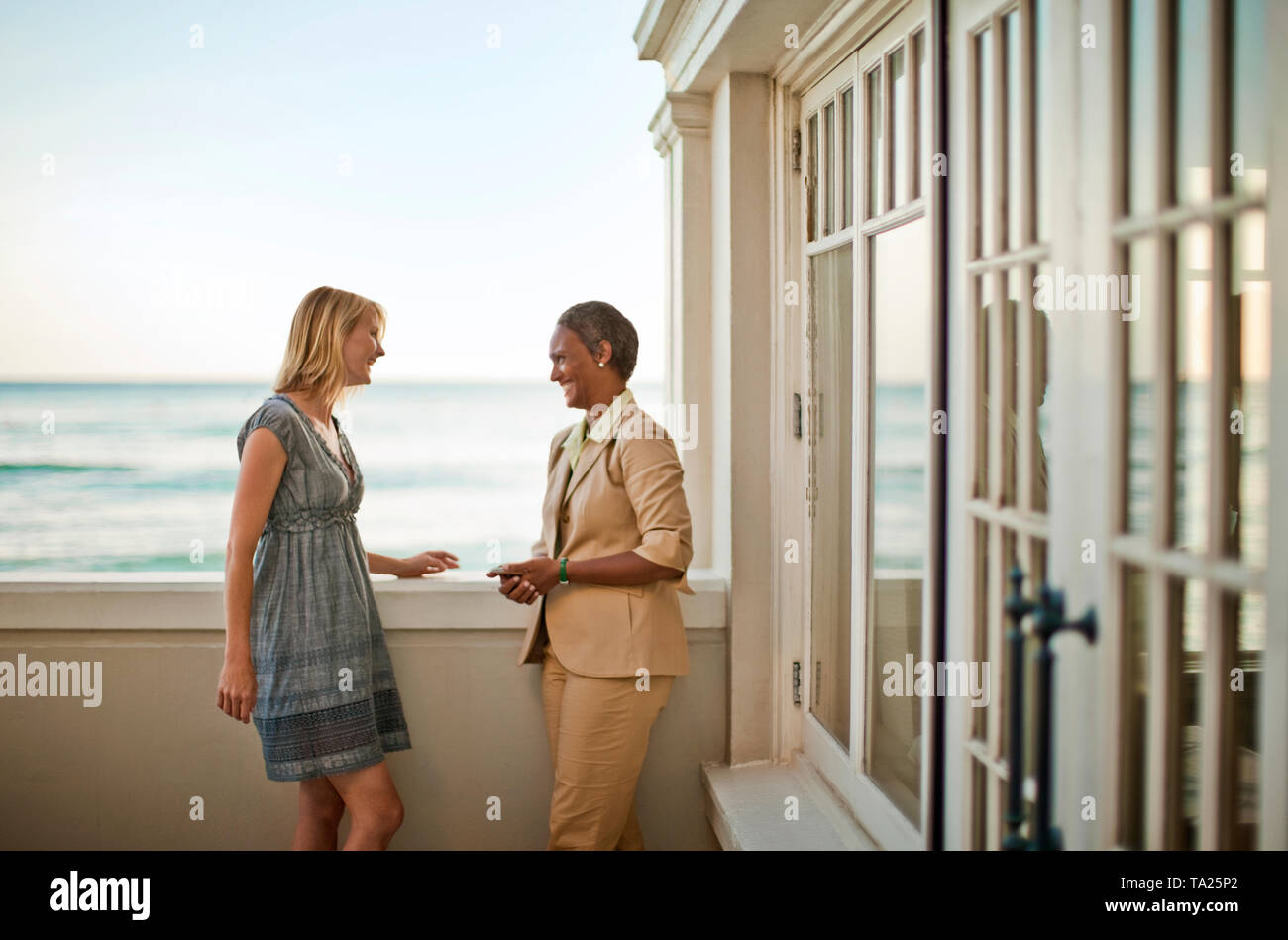 Two friends laughing together on hotel balcony Stock Photo - Alamy