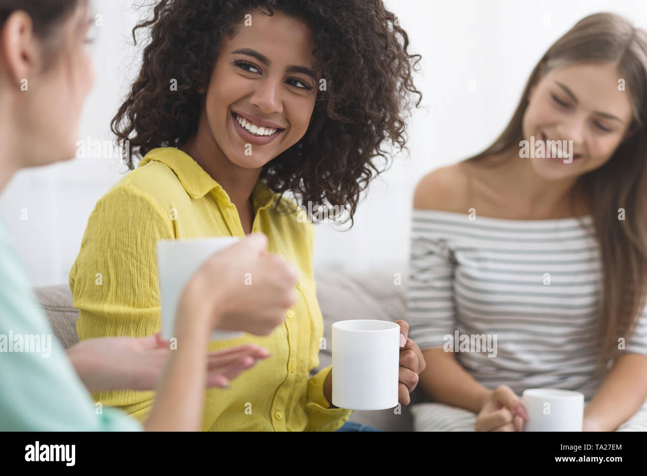 Happy girls drinking coffee and talking in living room Stock Photo - Alamy