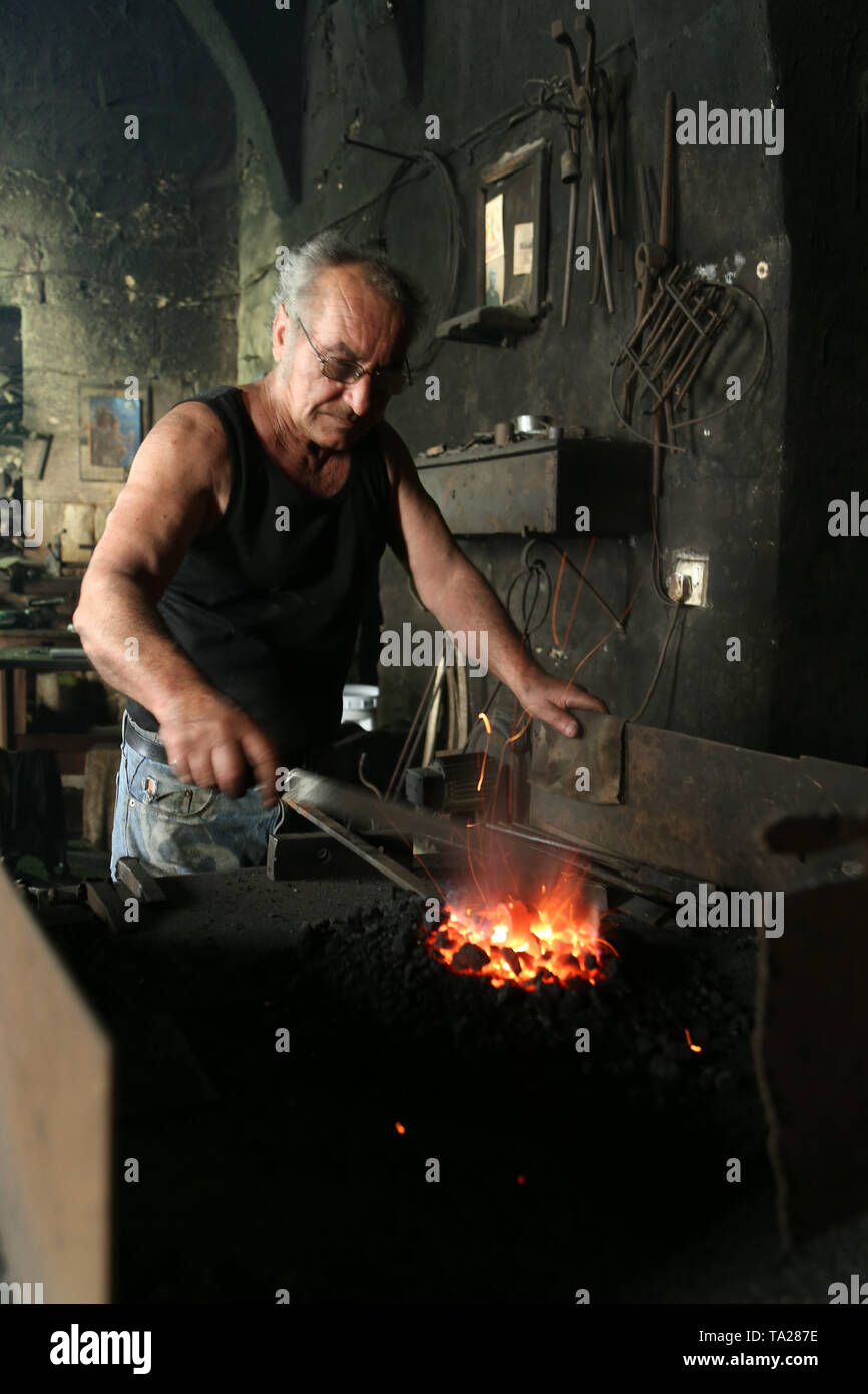 Blacksmith portrait at work in the workshop with fire. Gozo, Malta ...