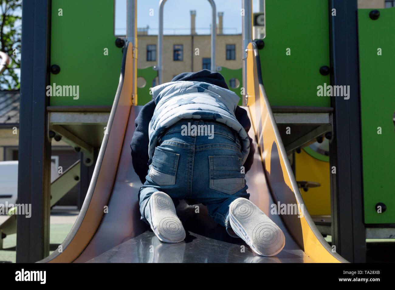 Child climbing a slide in a children's playground Stock Photo - Alamy