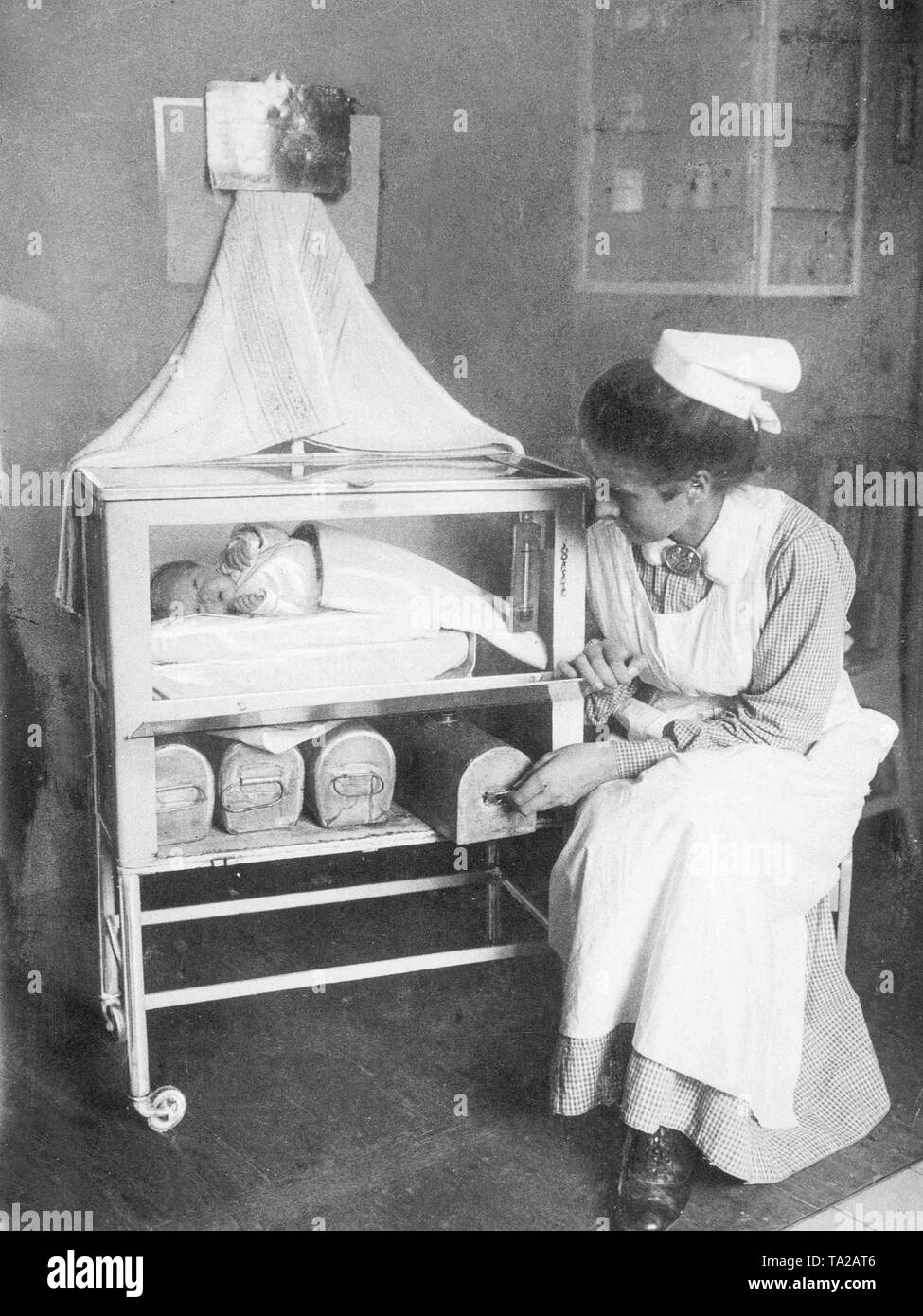 Picture of an incubator called couveuse for premature infants. A nurse ...