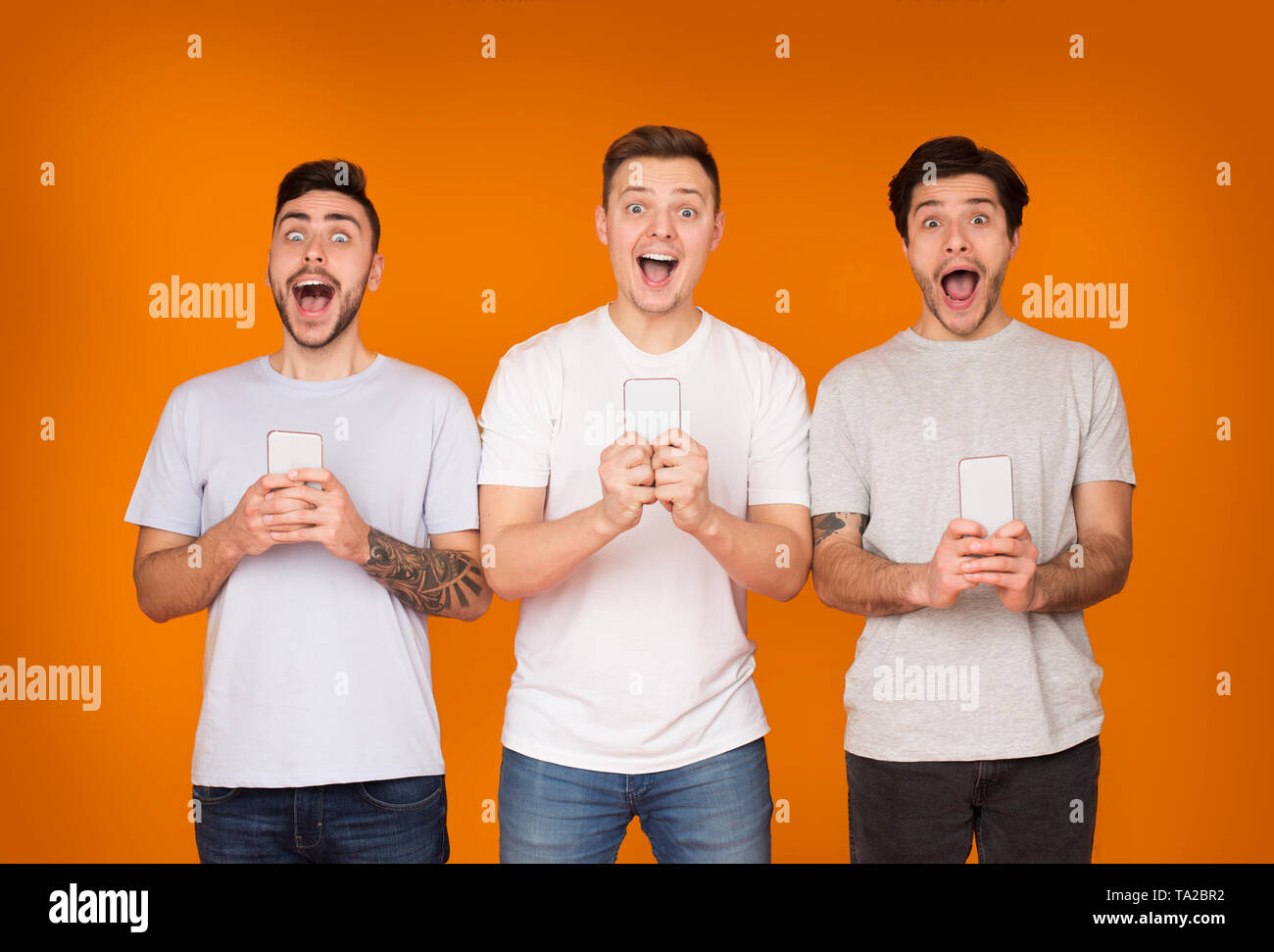 Shock Content. Friends With Phones Looking At Camera Stock Photo - Alamy