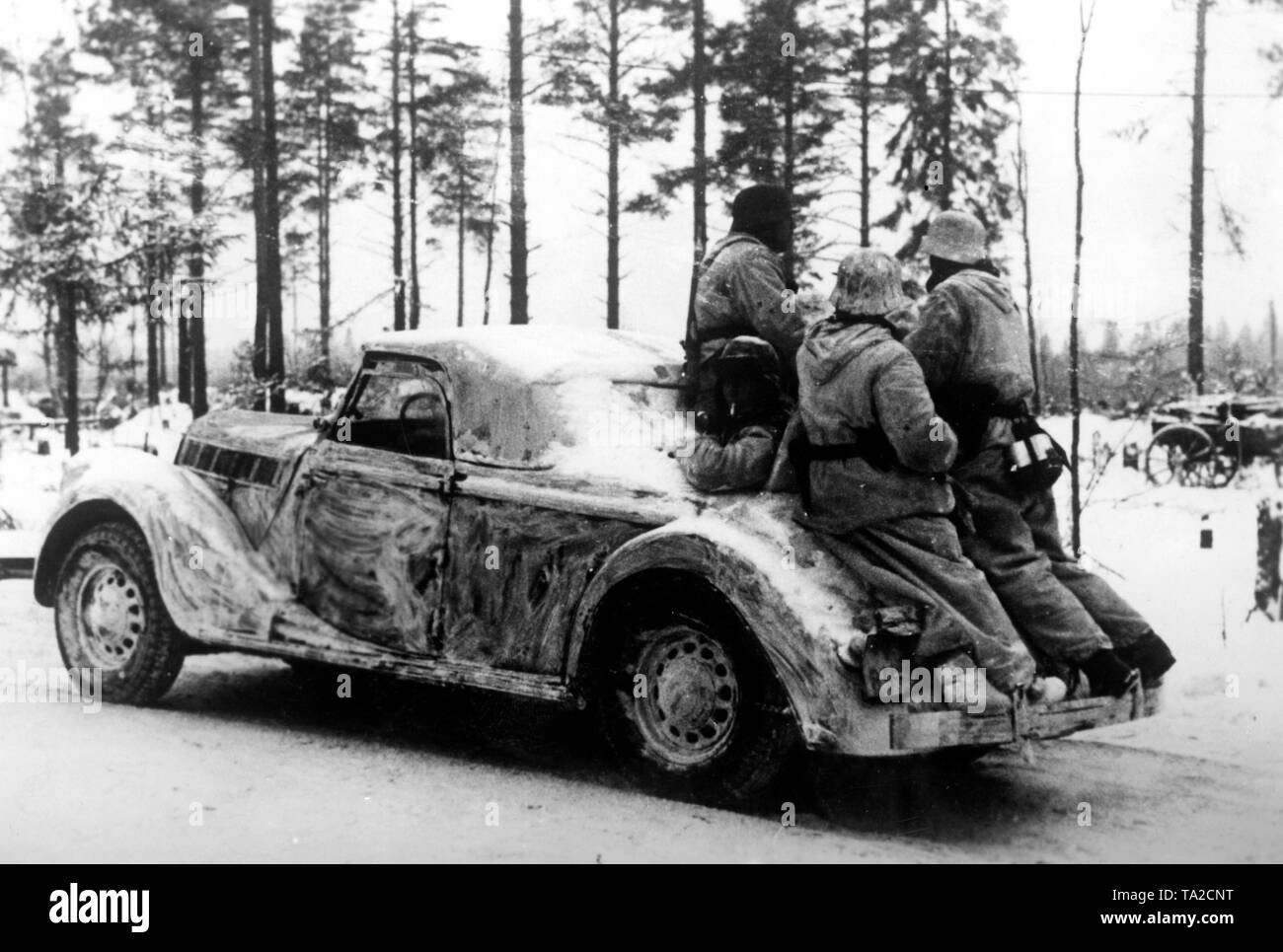Three German soldiers are taken away by a car. They sit outside on the ...