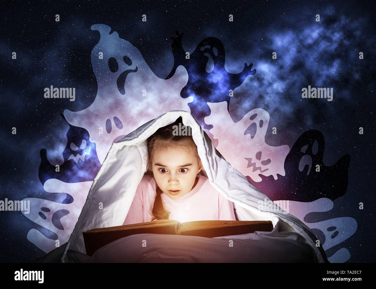 Scared little girl reading book in bed Stock Photo - Alamy