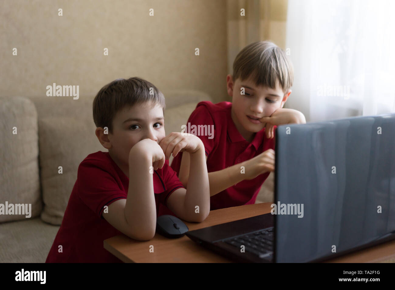 Two brothers are sitting in the living room and playing with the pc ...