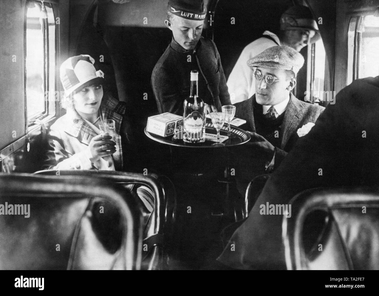 A Lufthansa steward serves passengers aboard an aircraft Stock Photo ...
