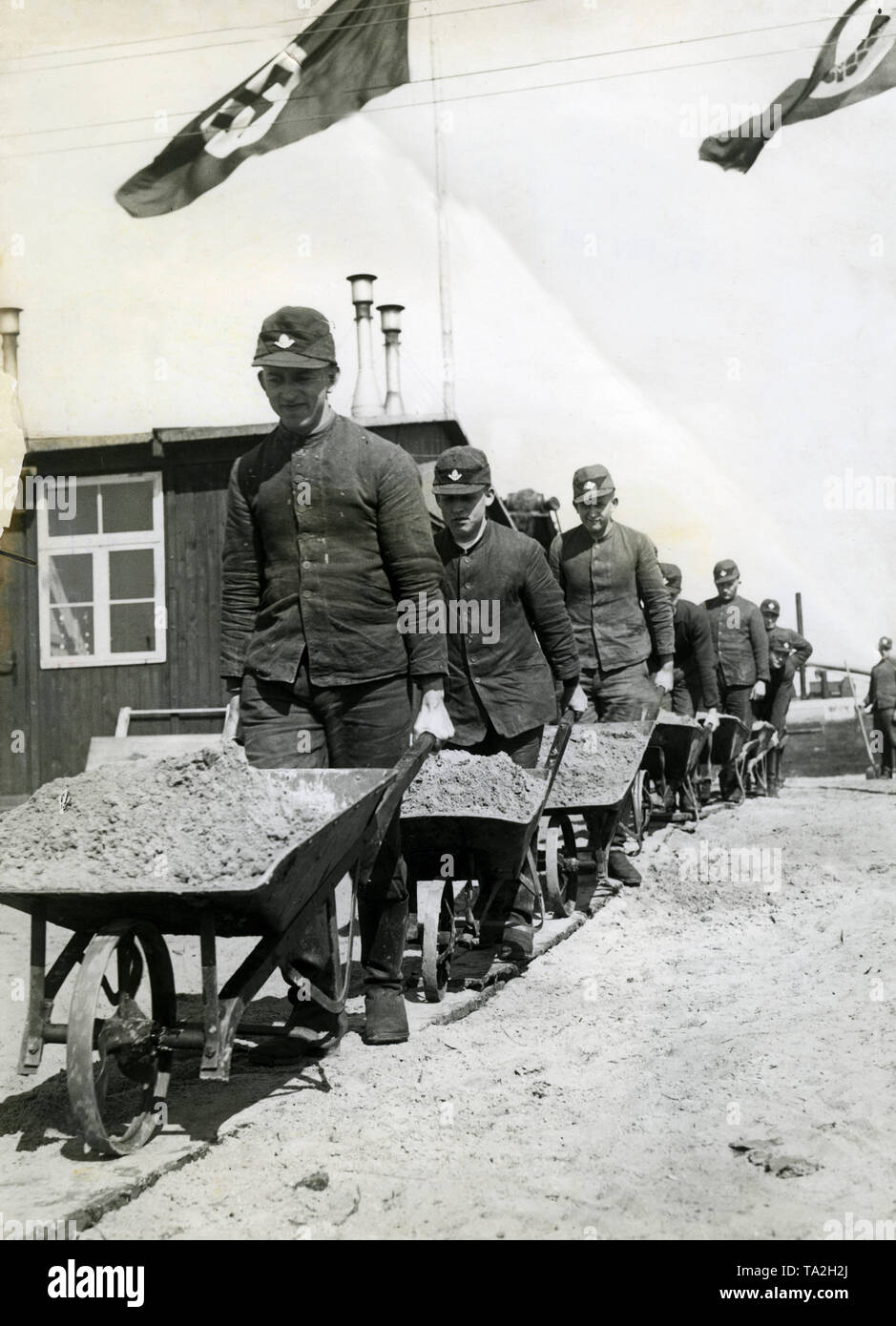 Members of the Voluntary Labour Service carry away rubbish in carts. On ...