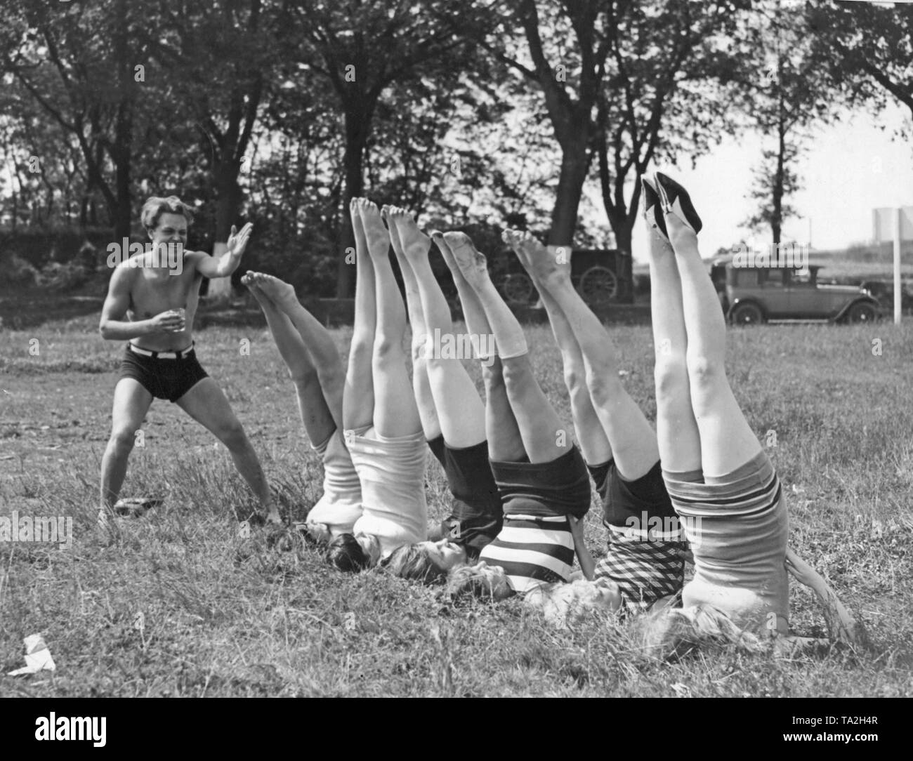 Women at the gym. They practice the shoulderstand while a teacher gives ...