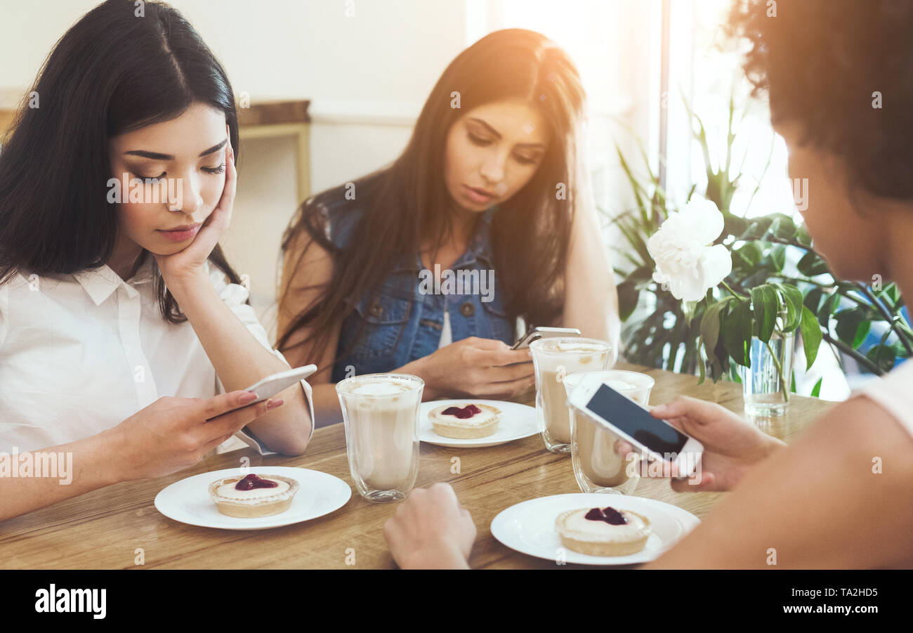 Young female friends using telephones and feel boring together Stock ...