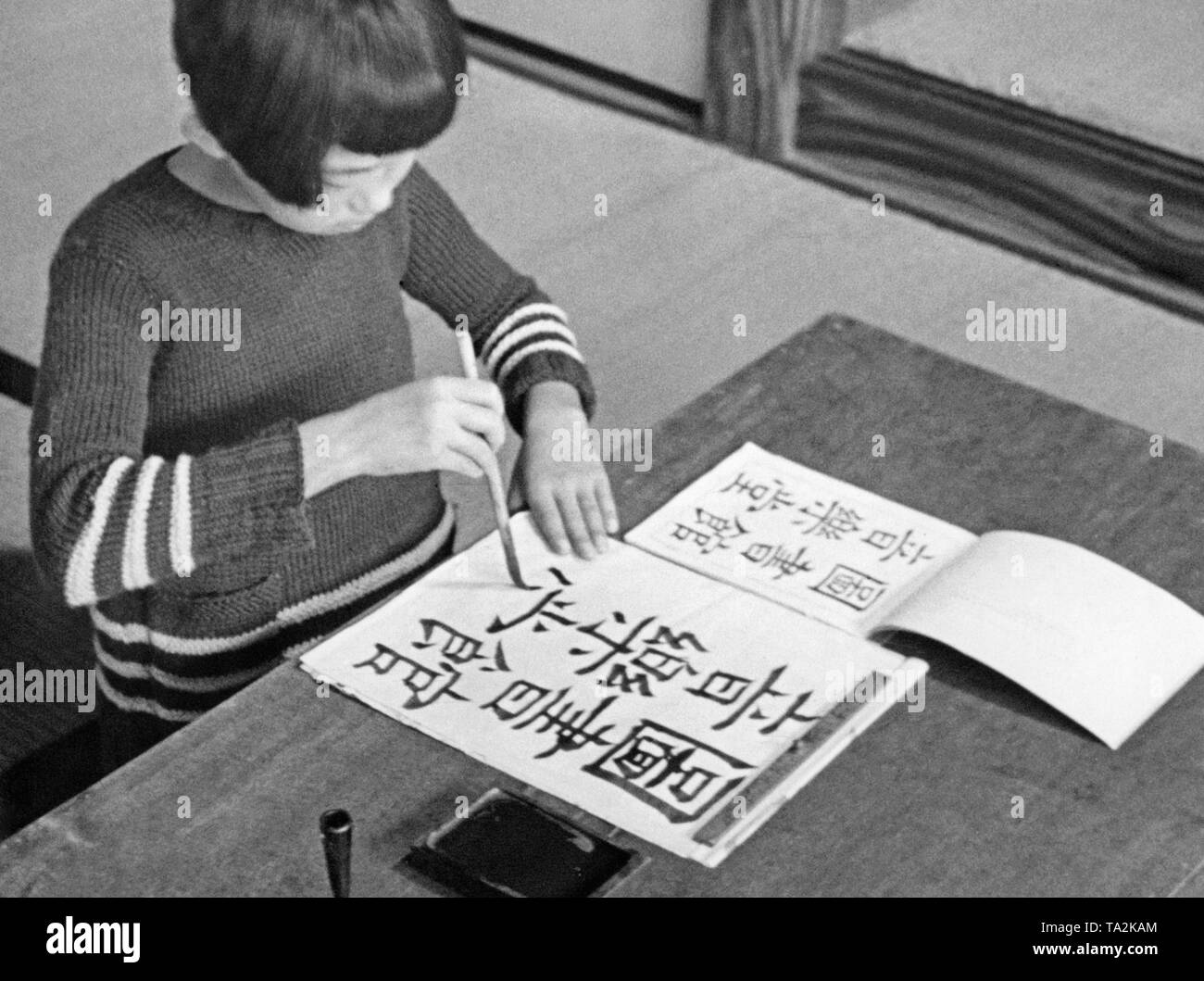 A Japanese kid practices writing with a brush Stock Photo - Alamy