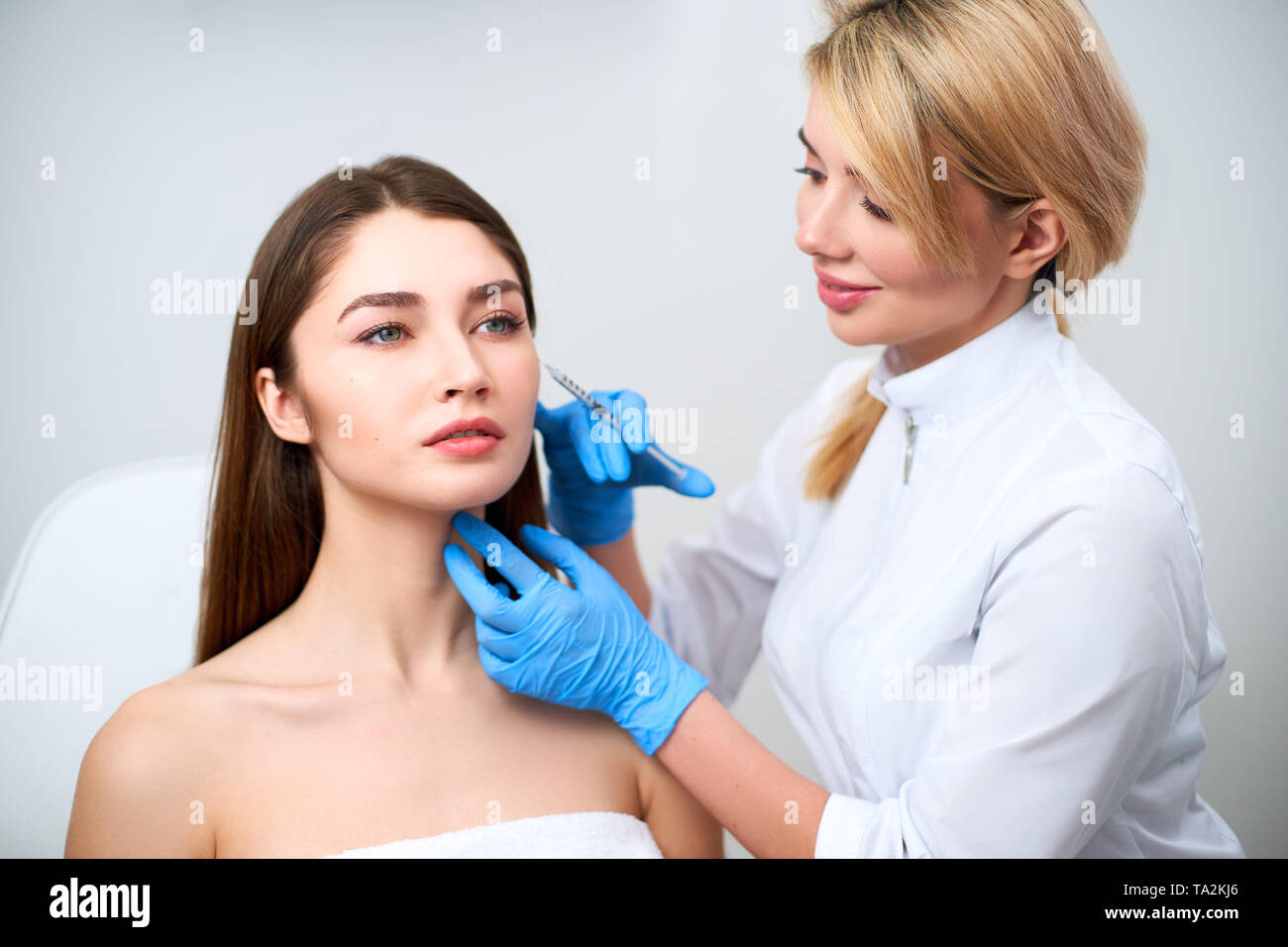 Beautician doctor with botulinum toxin syringe making injection to to ...