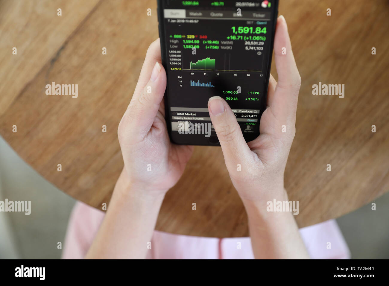 Female hand with smartphone trading stock online in coffee shop ...