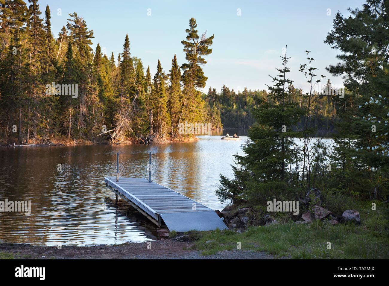 A typical northern Minnesota lake with a dock and fishermen in the ...