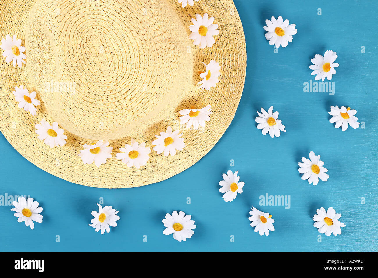 Straw hat with a camomile on a blue background. Top view. Summer ...