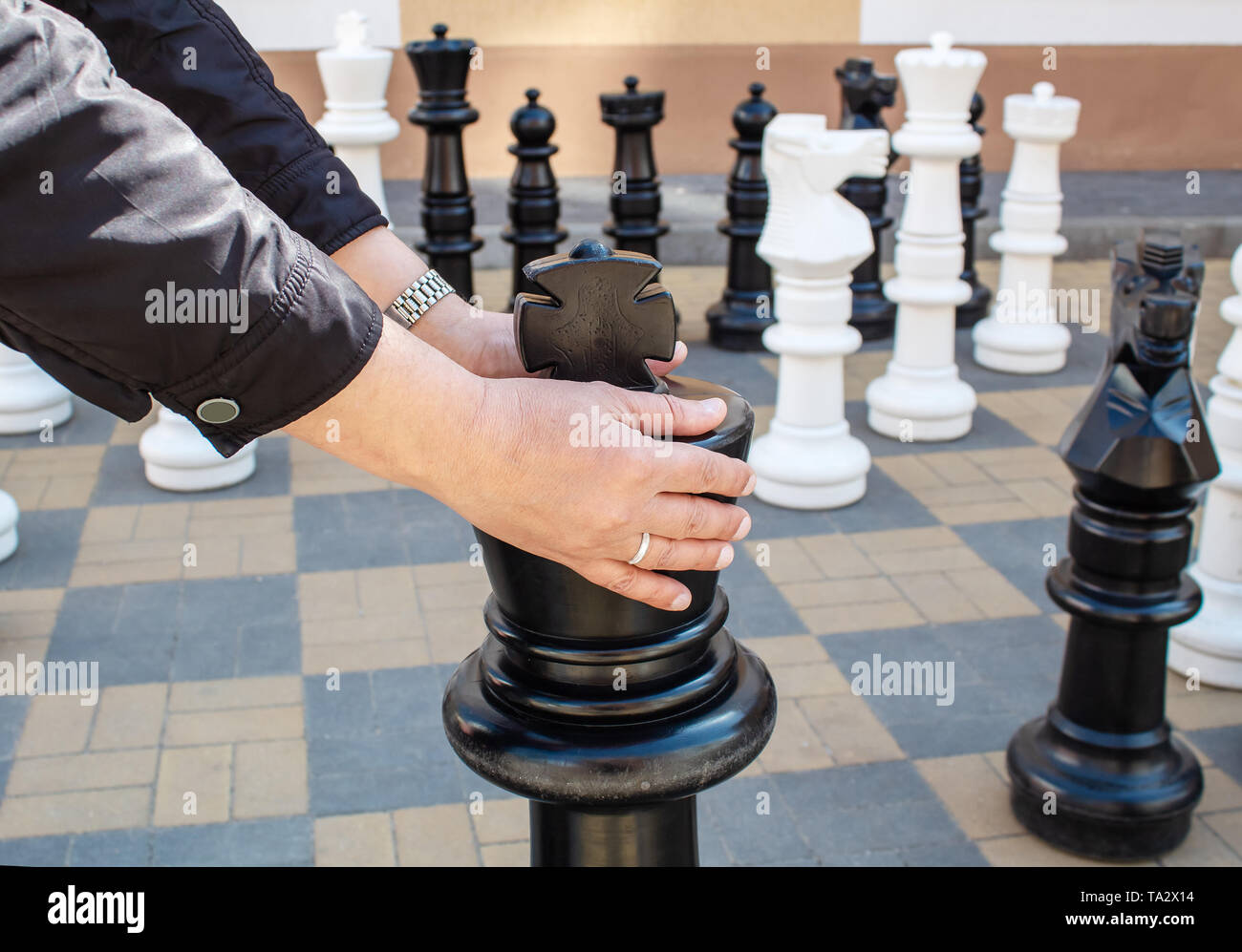 man moving giant chess piece king outdoor on the city street. hands ...