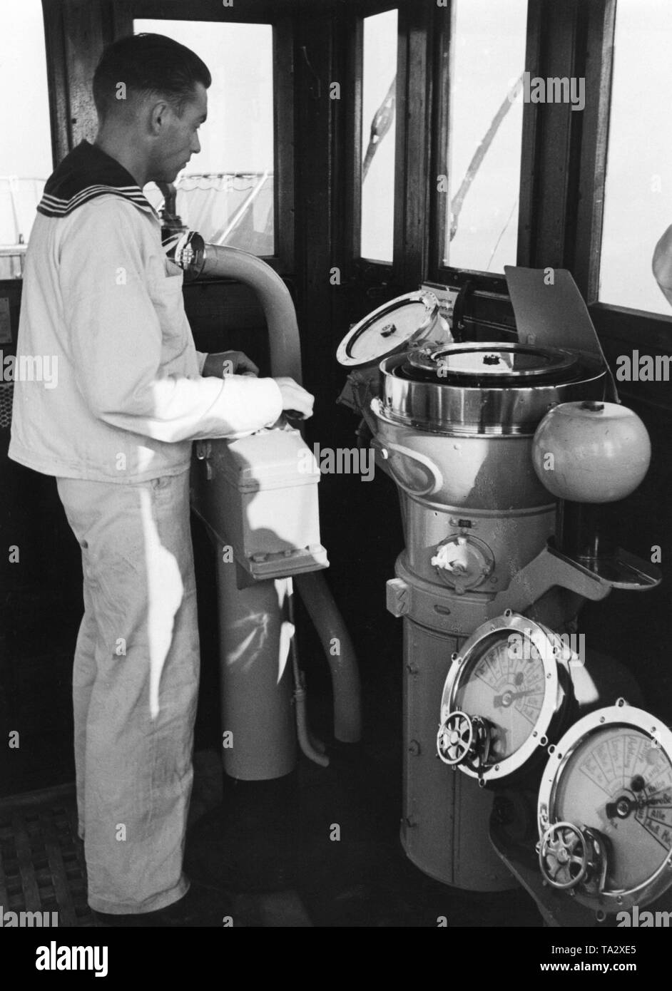 Look into the wheelhouse of the ship, a member of the crew is at the ...
