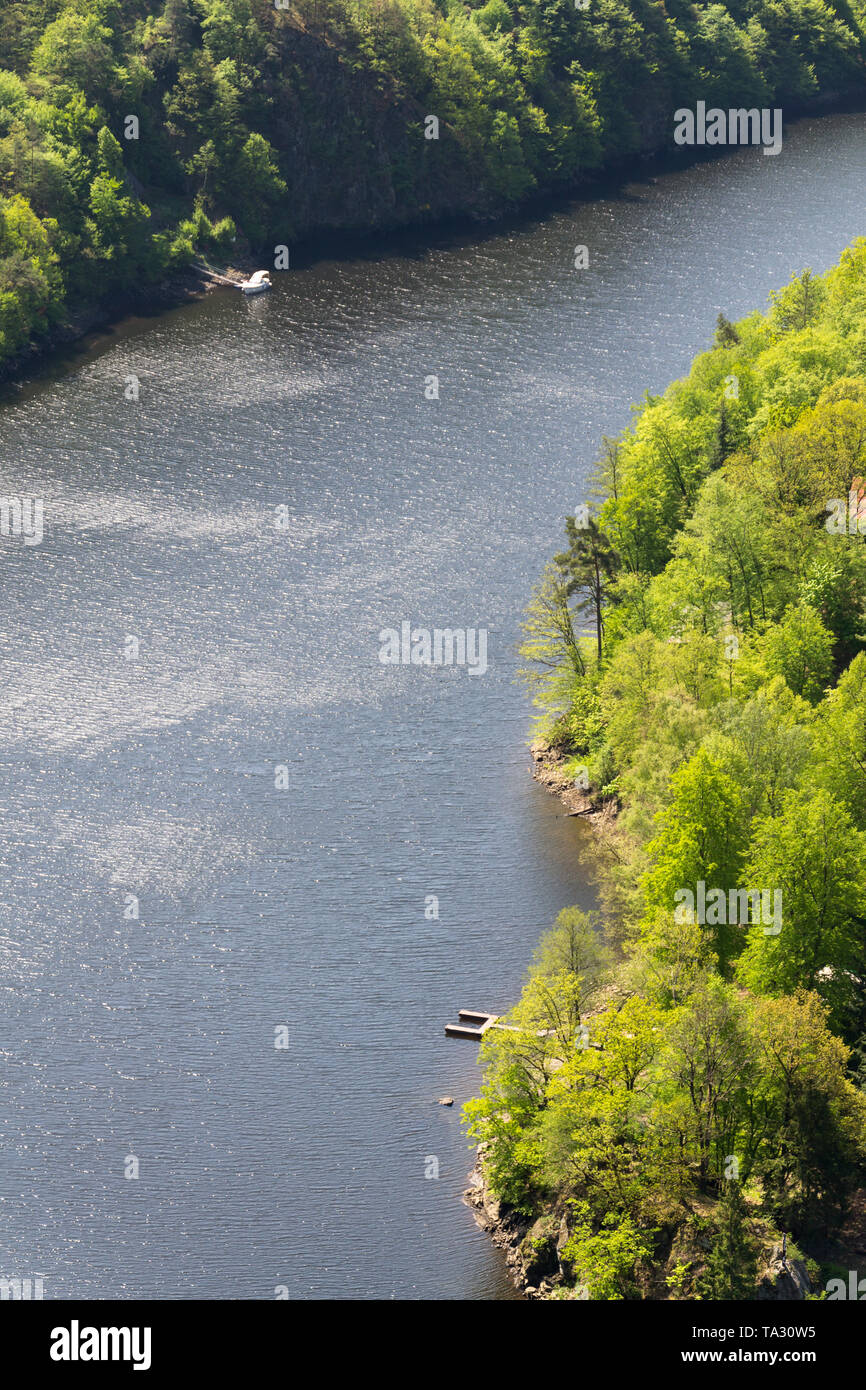 Single ship and lonely pier on river, breathtaking green woods nature ...