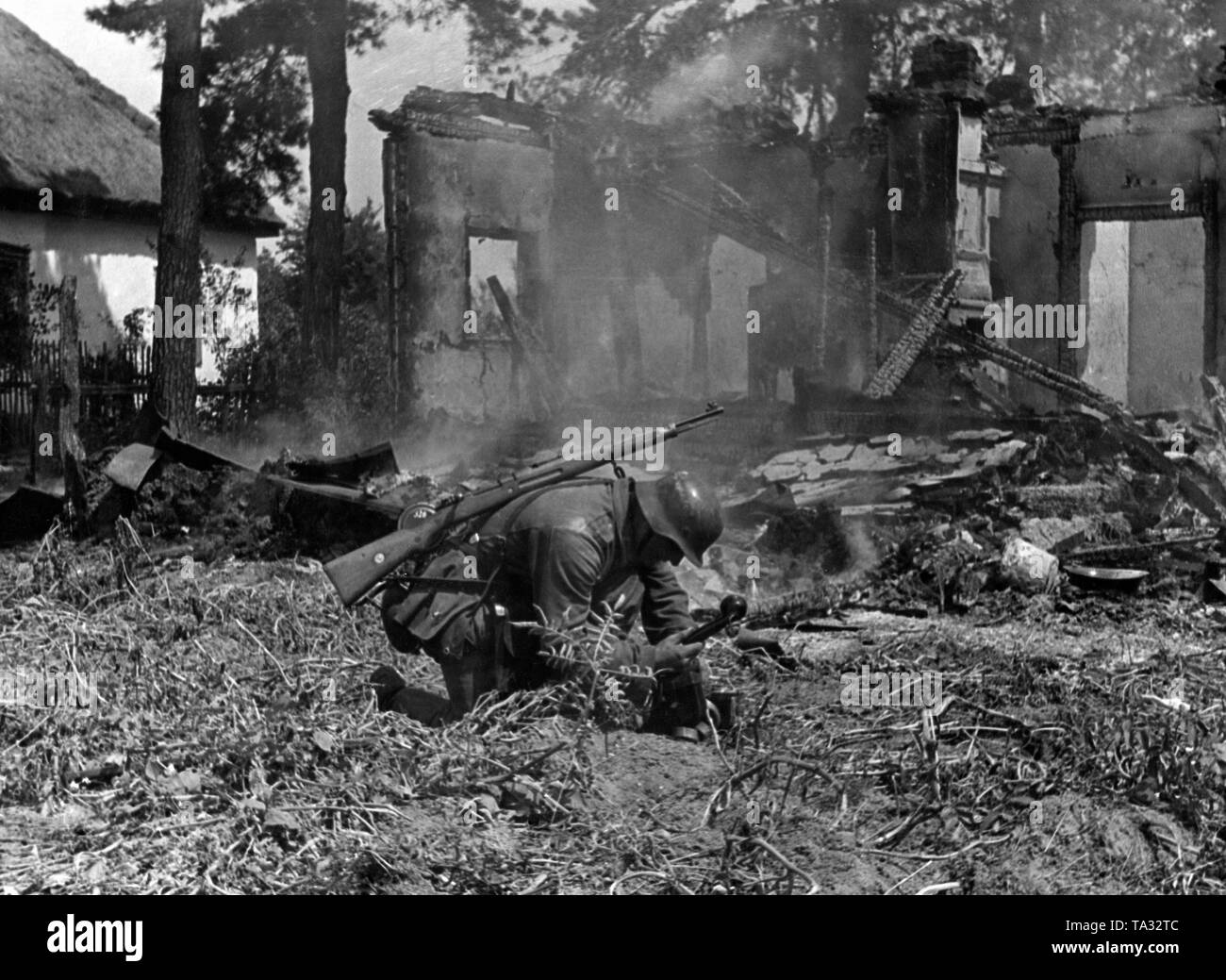 A soldier of a signal troops lays a field telephone in the rubble of a ...