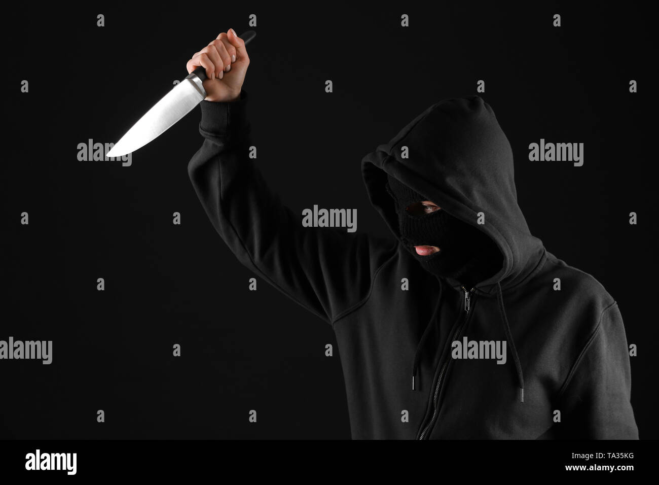 Bandit with knife on dark background Stock Photo - Alamy