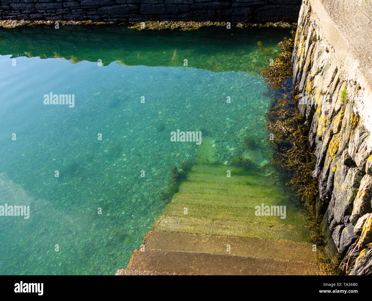 concrete steps leading into clear blue water Stock Photo - Alamy
