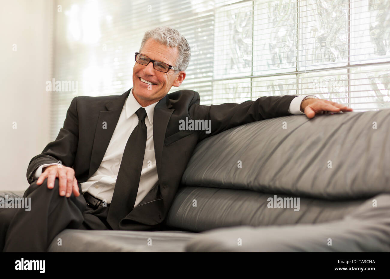 Man sitting on sofa and smiling hi-res stock photography and images - Alamy
